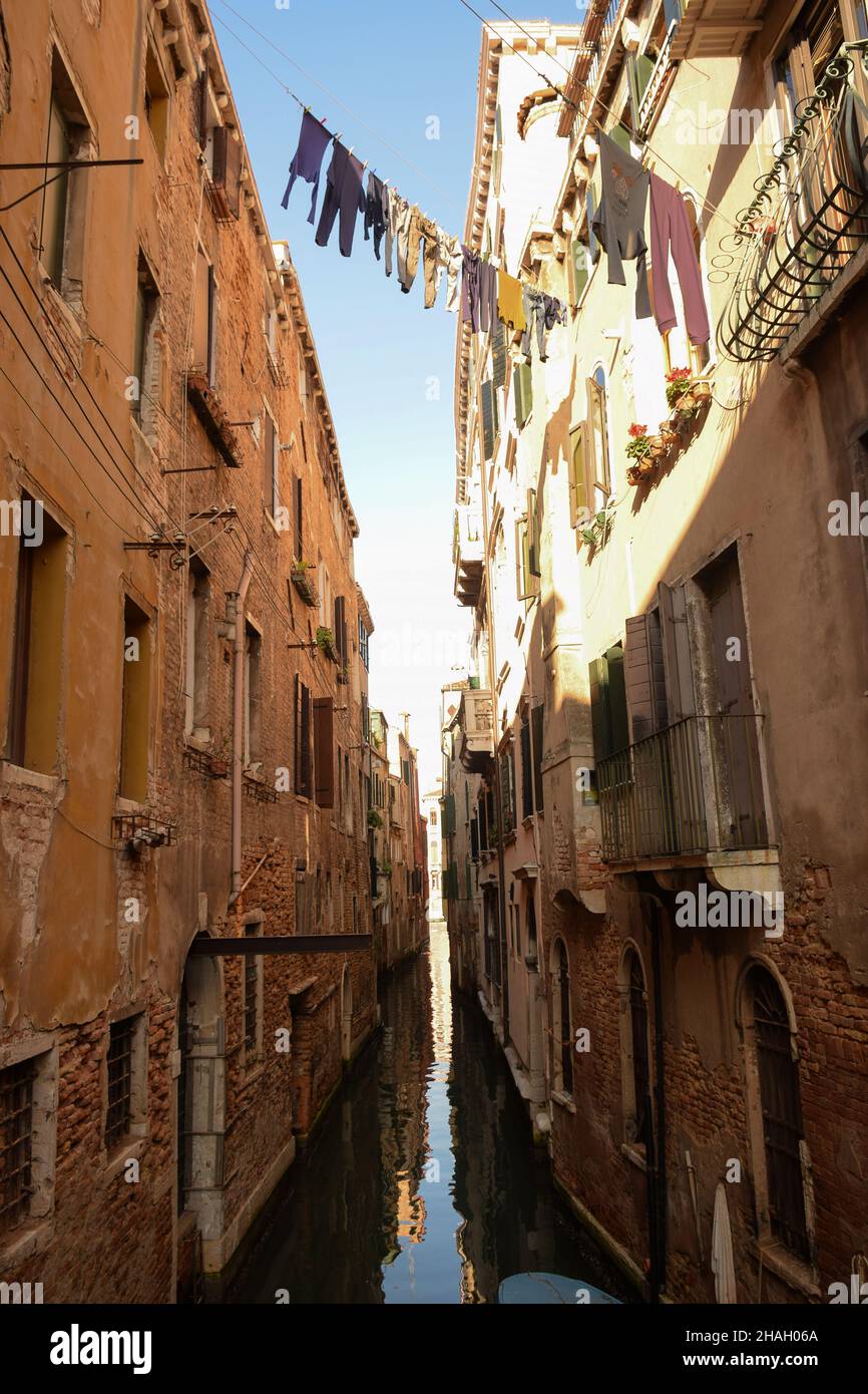 A canal in Venice, Italy, between old buildings with washed residents ...