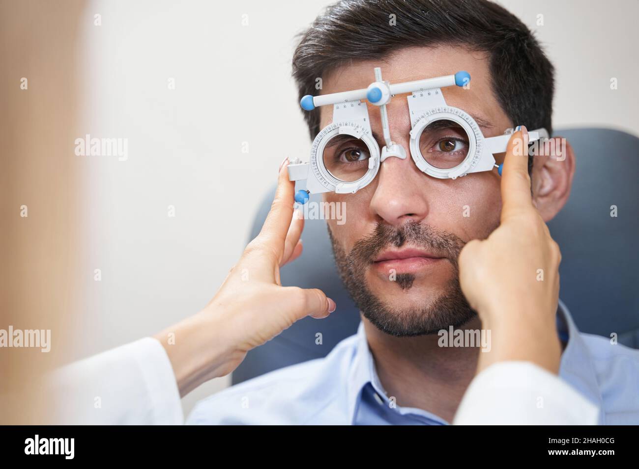 Oculist putting trial frame on man eyes Stock Photo - Alamy