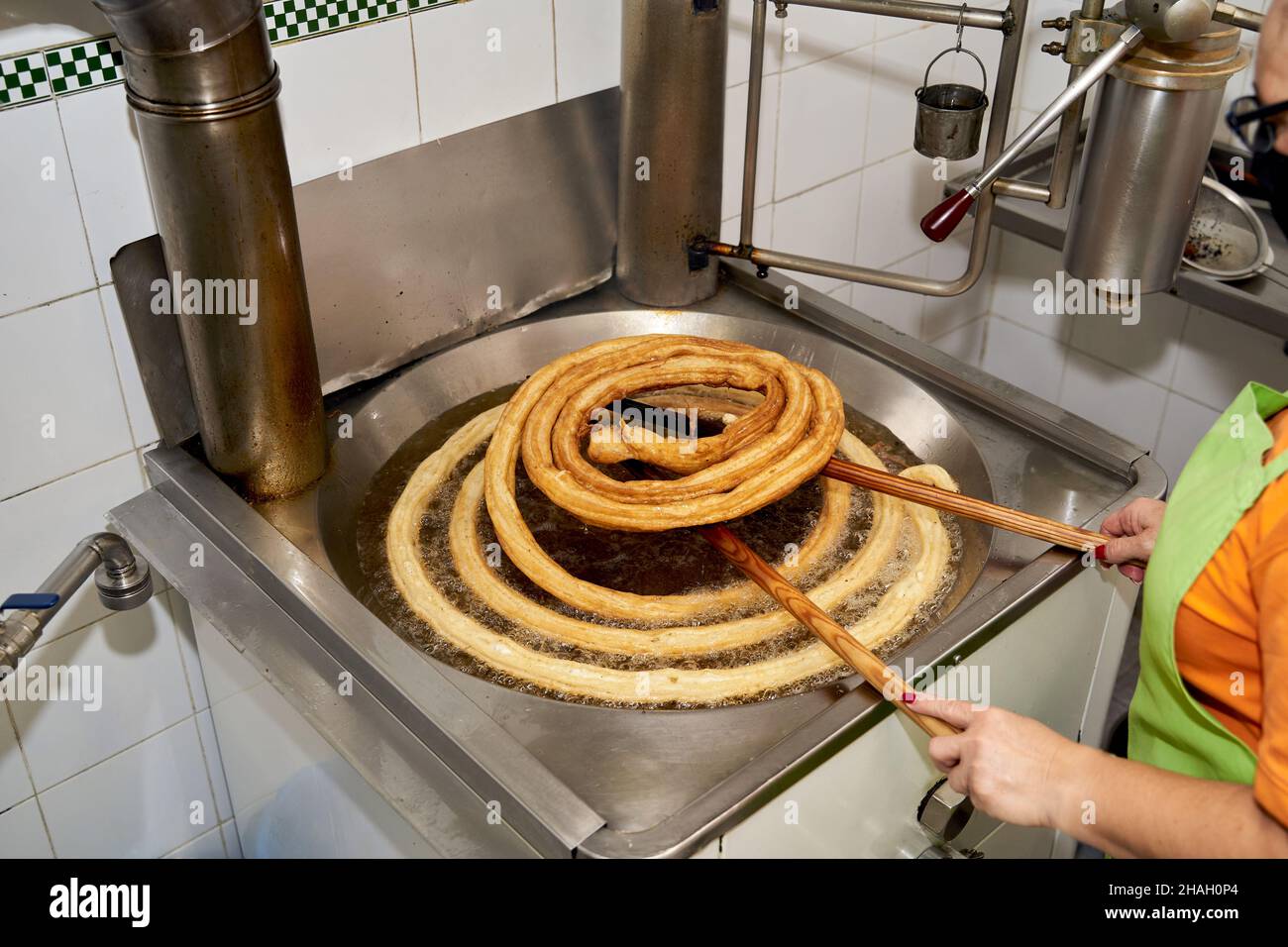 Anonymous cook in apron holds cooked churro dough with chopsticks to ...