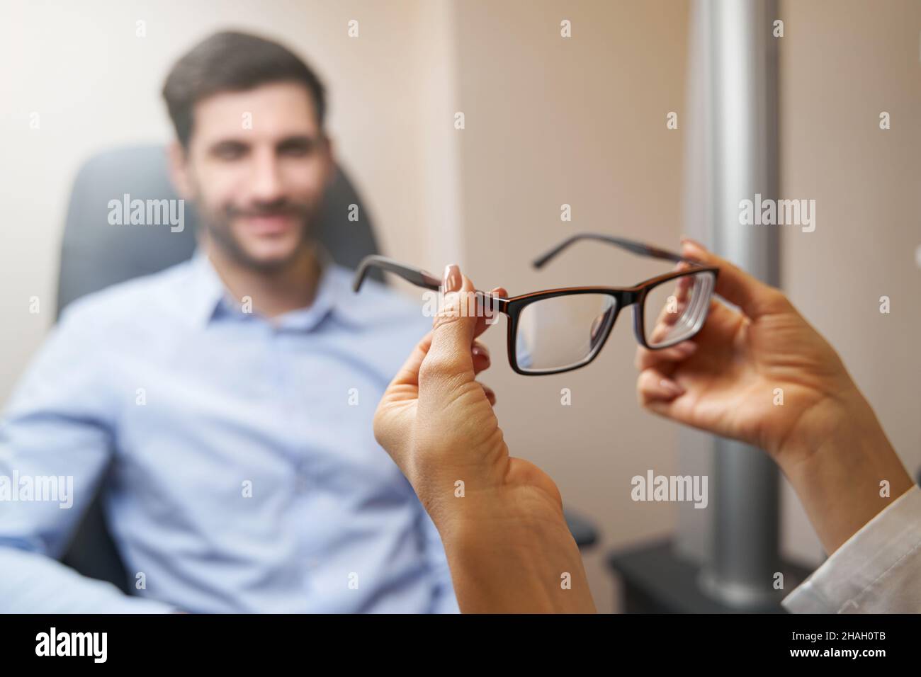 Optometrist bringing pair of glasses to patient Stock Photo - Alamy