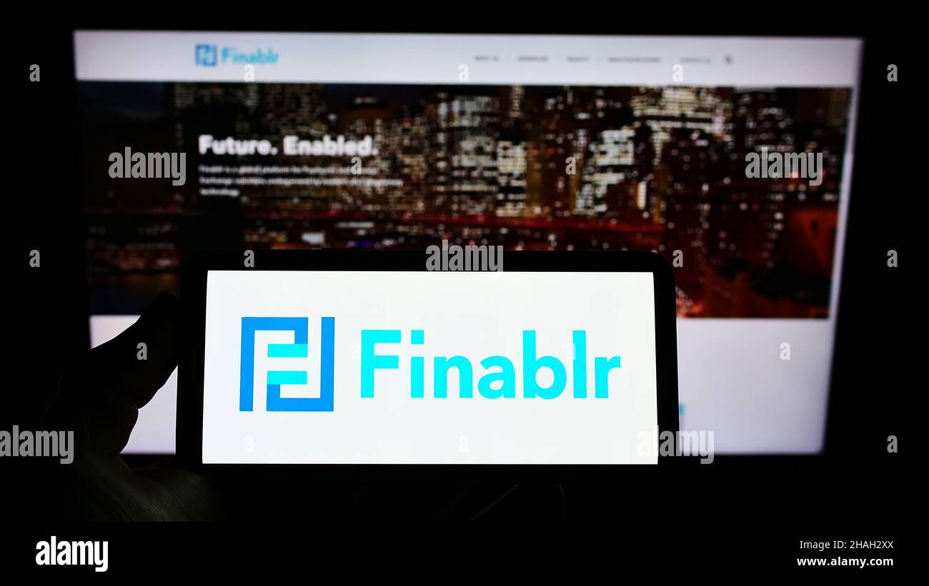Person holding smartphone with logo of payment platform company Finablr ...