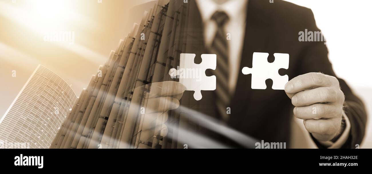 Hands joining two puzzle pieces, teamwork concept; multiple exposure ...