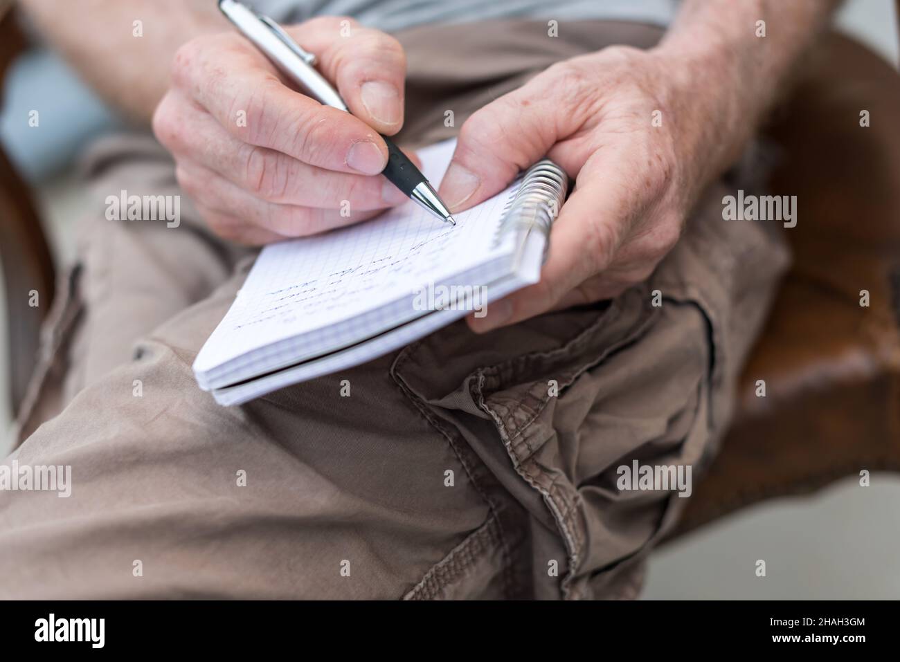 Man sitting outdoor taking notes on a pocket book Stock Photo - Alamy