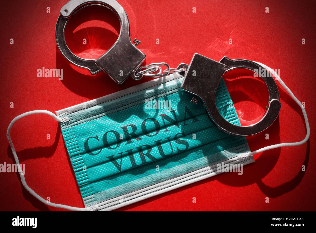 Handcuff laying on a face mask in a red background with the text ...