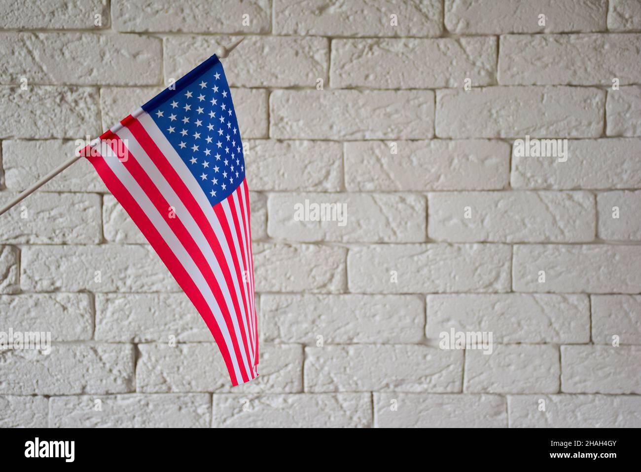 On the left side of the frame is the USA flag on a light brick wall ...
