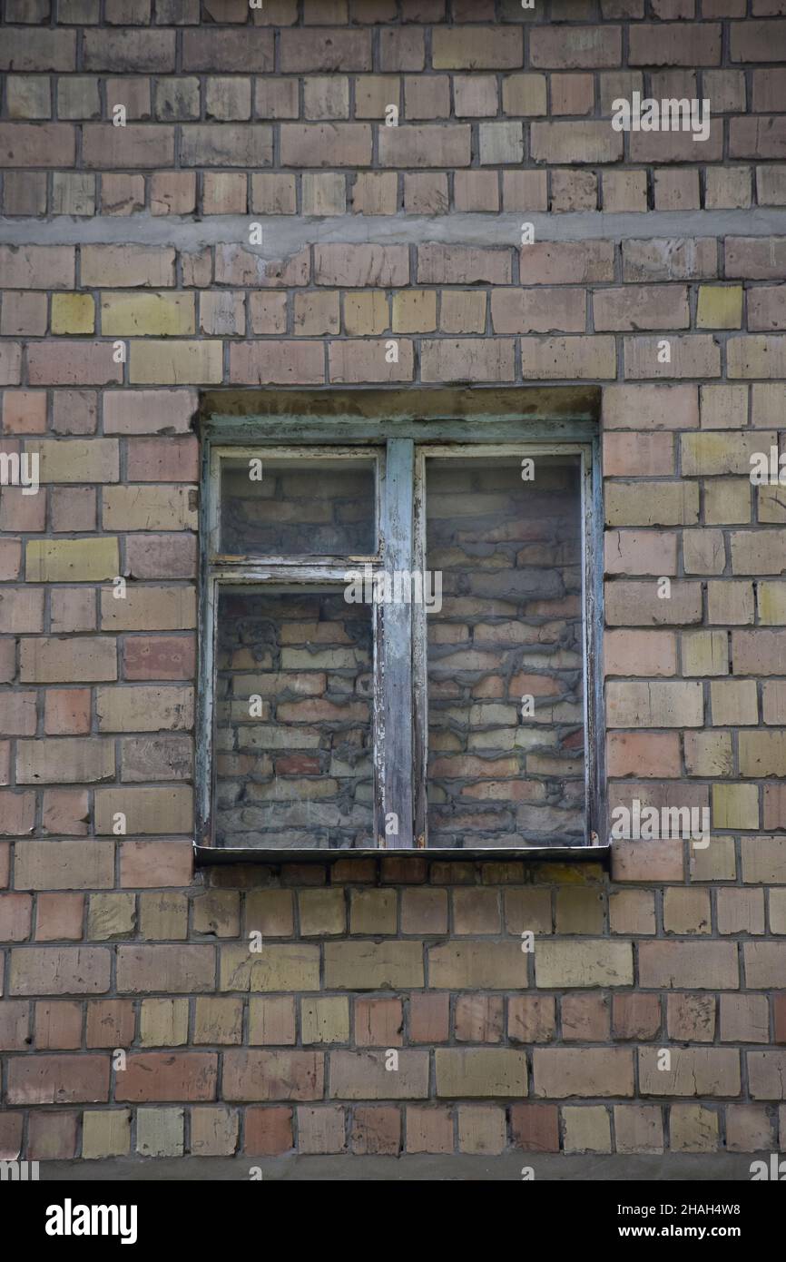 In the center of the brick wall there is an old window completely ...