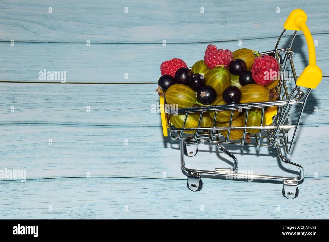 Raspberries, gooseberries and currants are heaped in a small yellow toy ...