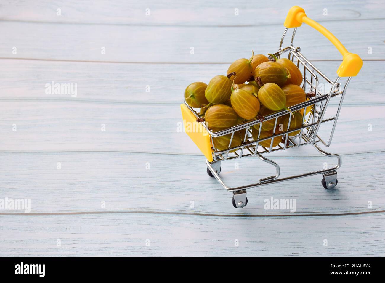 Gooseberries are stacked in a small toy yellow shopping cart. On the ...