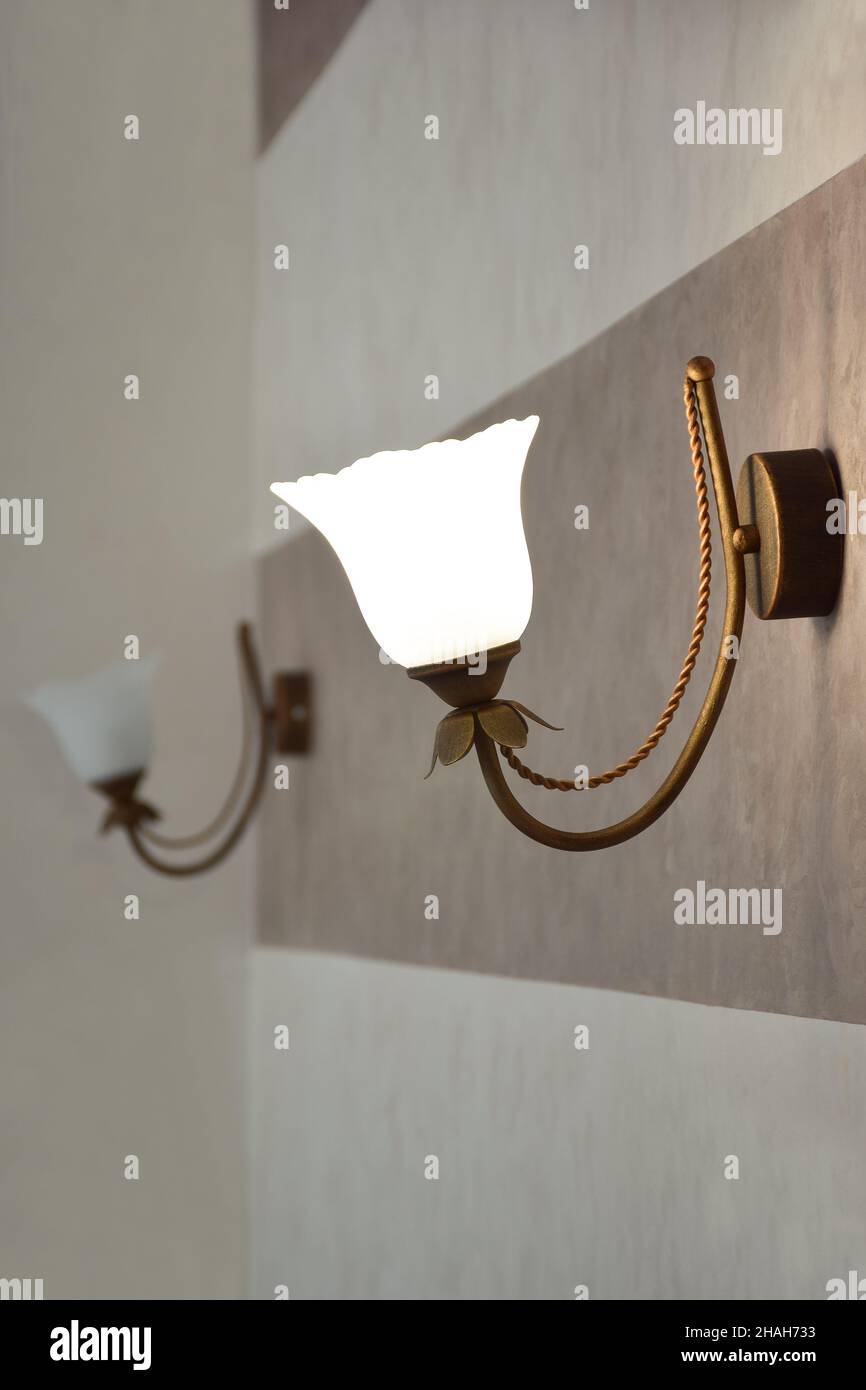 Two electric wall lights hang on the right side of the painted wall of ...