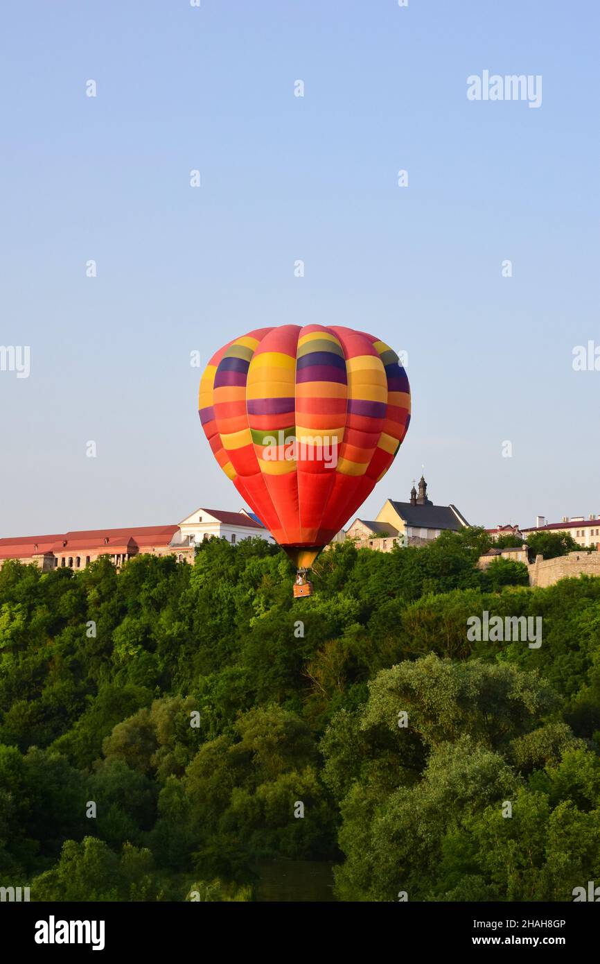 A large multi-colored balloon flies very low over the river and between ...