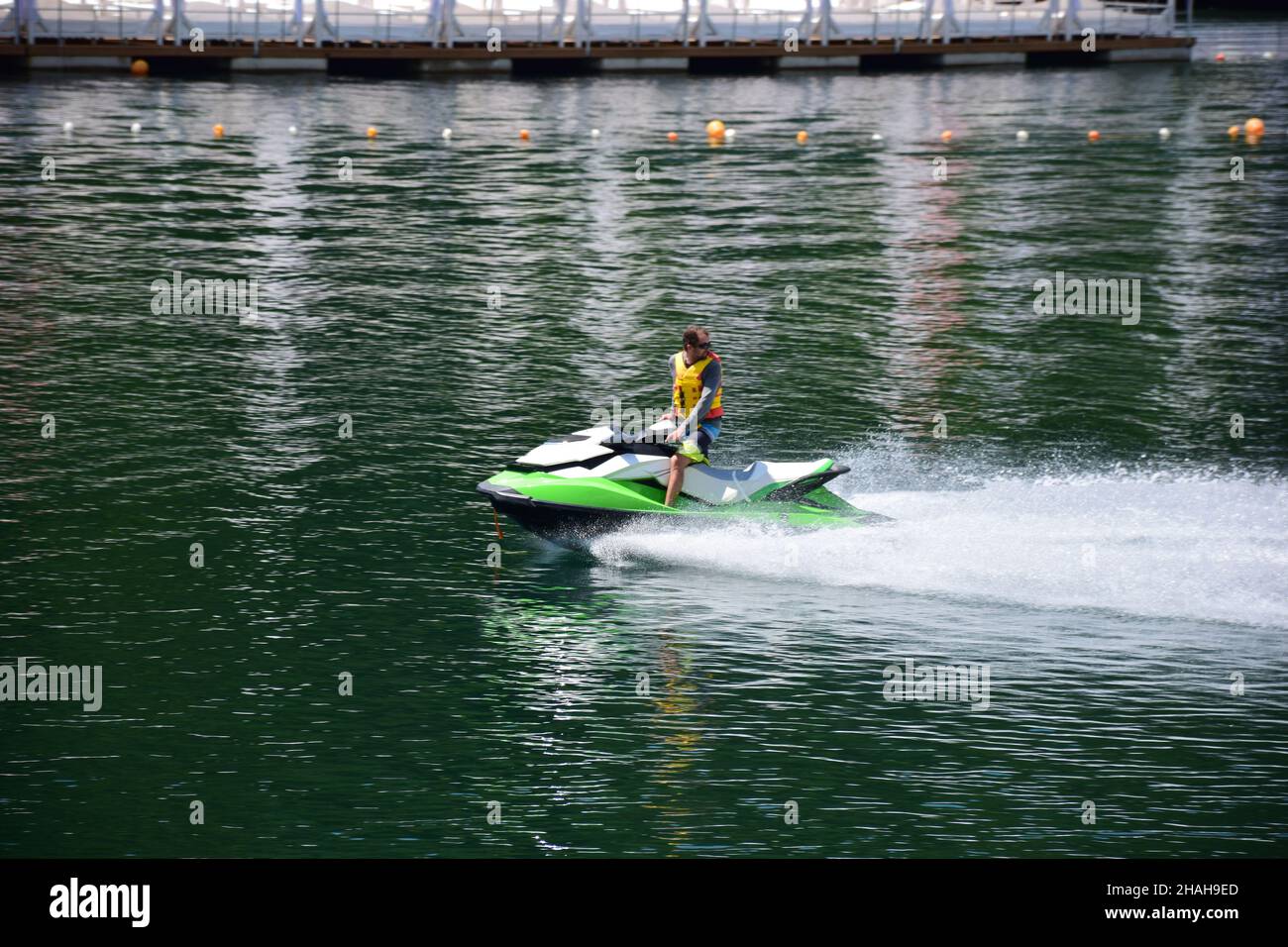 A jet ski with a man in a life jacket floating on it quickly rushes ...