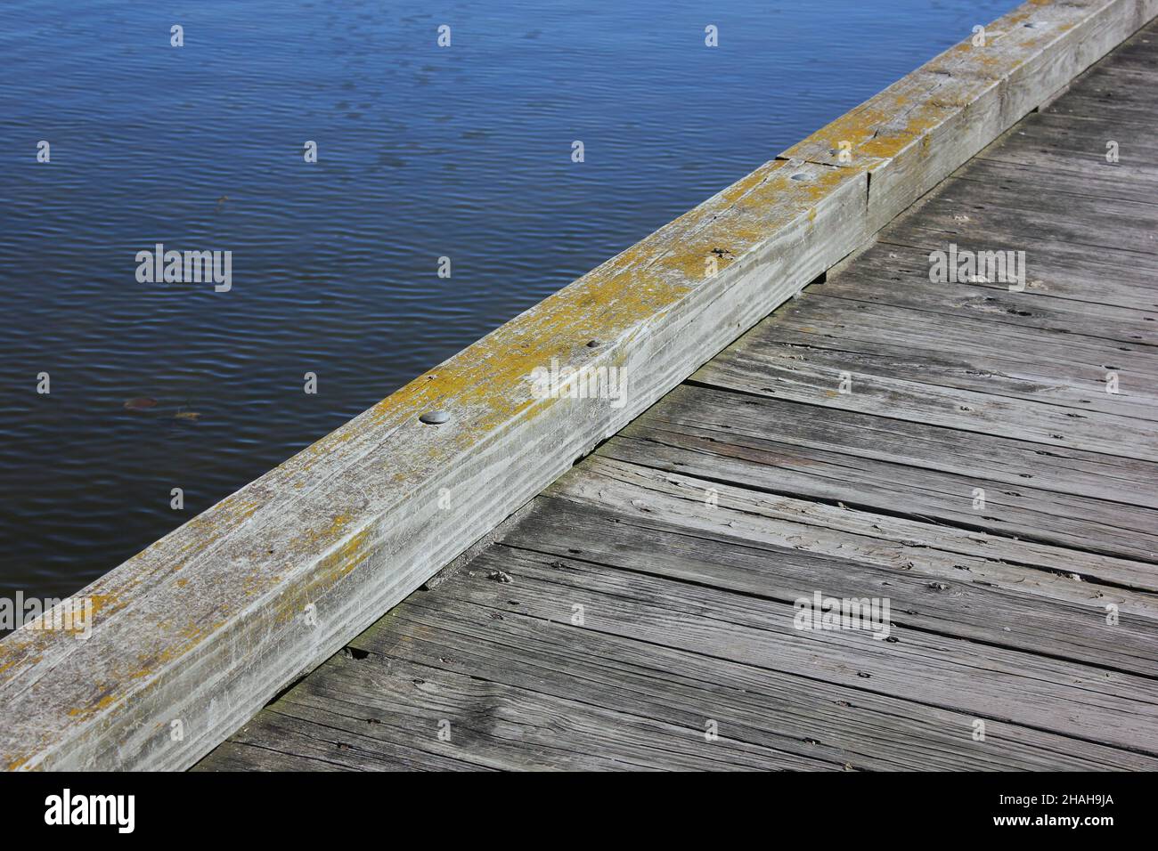 Minimalist view of a weathered gray wooden boardwalk crossing the lake ...