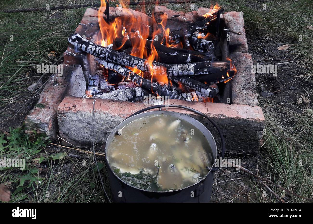 Fish soup cooked over a fire, cooked in a large saucepan next to a ...