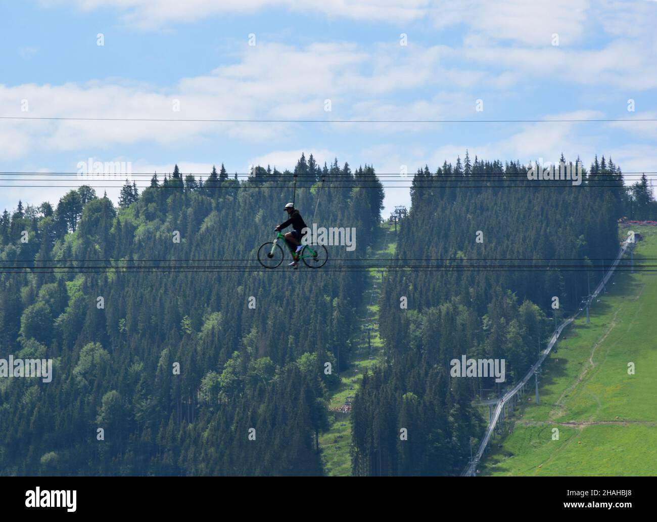 The guy rides a bicycle on a tightrope, wearing a helmet at a high ...