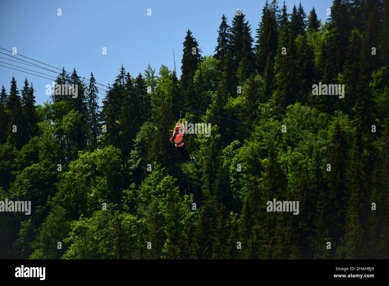 A girl of unrecognizable appearance descends a tightrope on a zipline ...