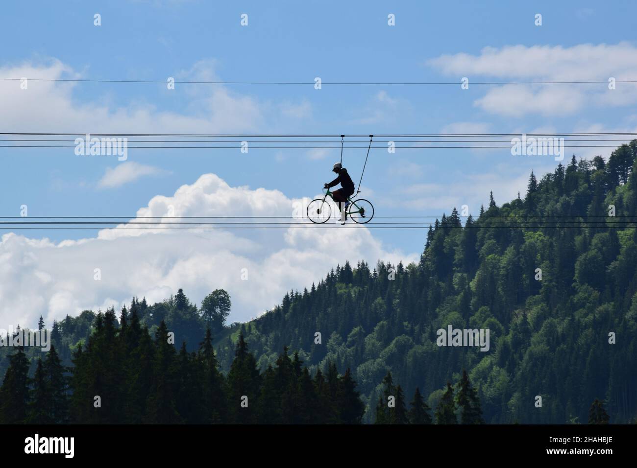 The guy rides a bicycle on a tightrope, wearing a helmet at a high ...