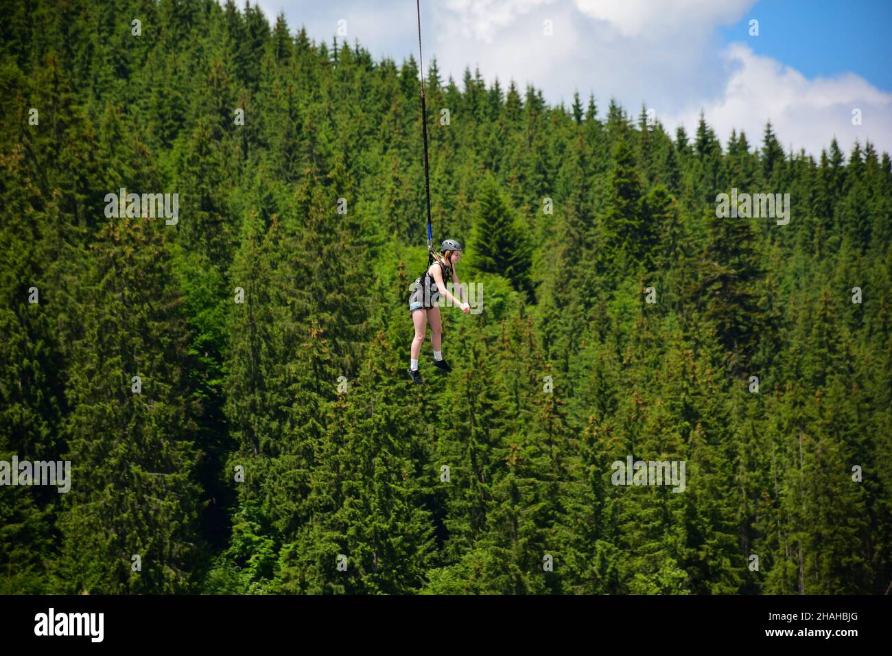 The girl jumped from the bungee jumping ride, hangs on a tight rope at ...