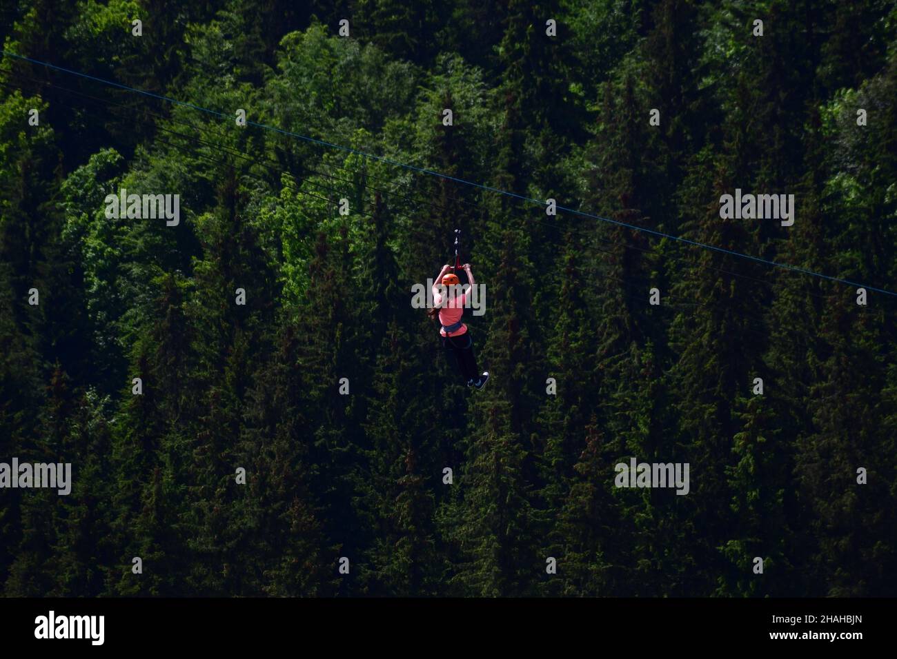 A girl of unrecognizable appearance descends a tightrope on a zipline ...