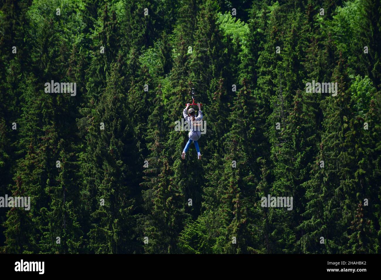 A girl of unrecognizable appearance descends a tightrope on a zipline ...