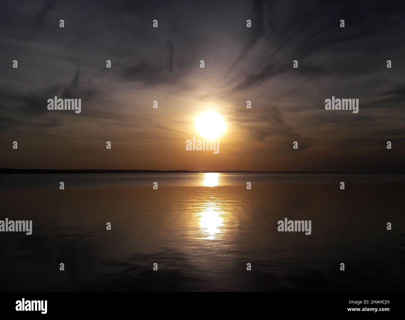 Sea surface of water without waves at sunset with not a bright sun ...