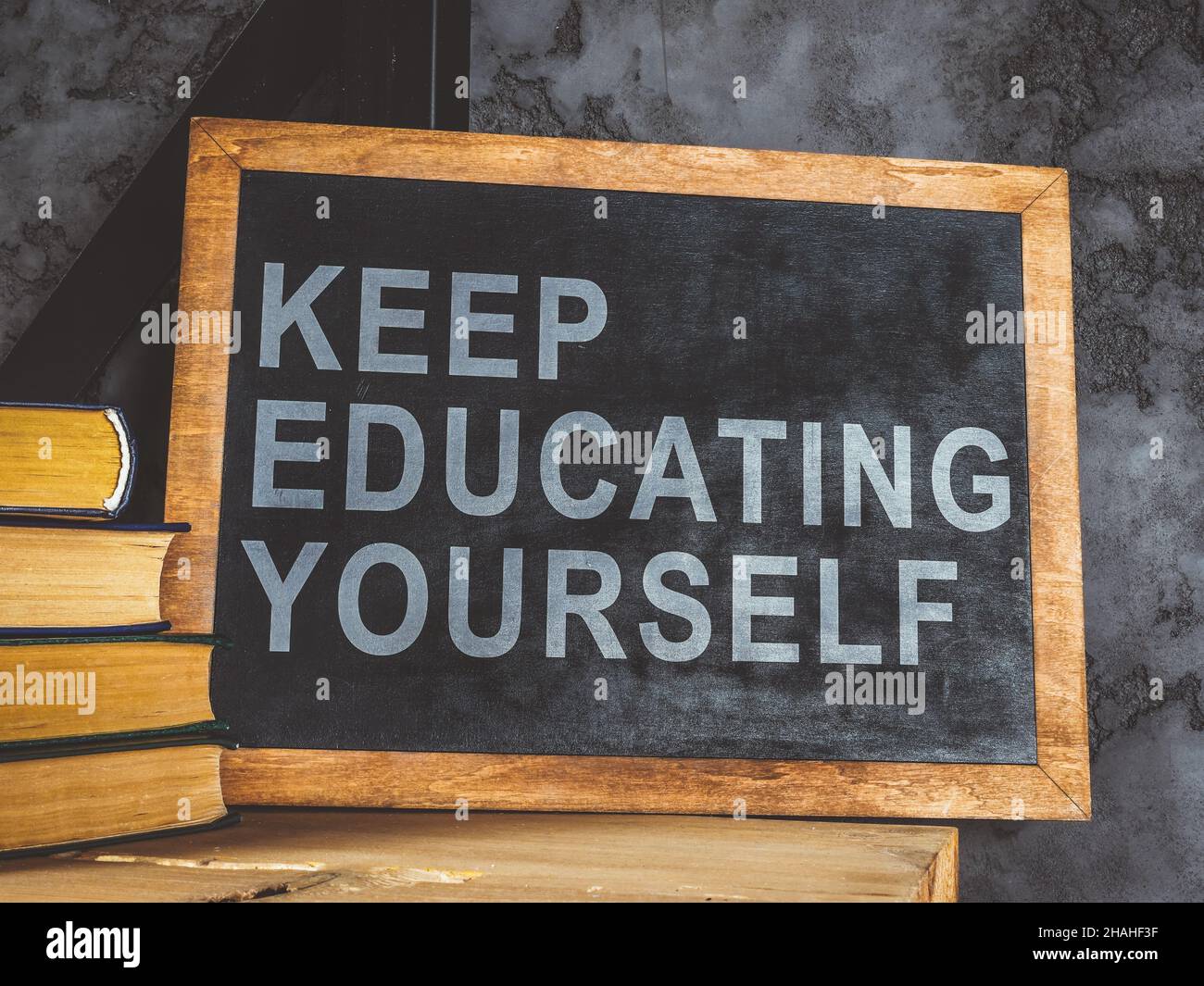 Blackboard near wall with words Keep educating yourself Stock Photo - Alamy