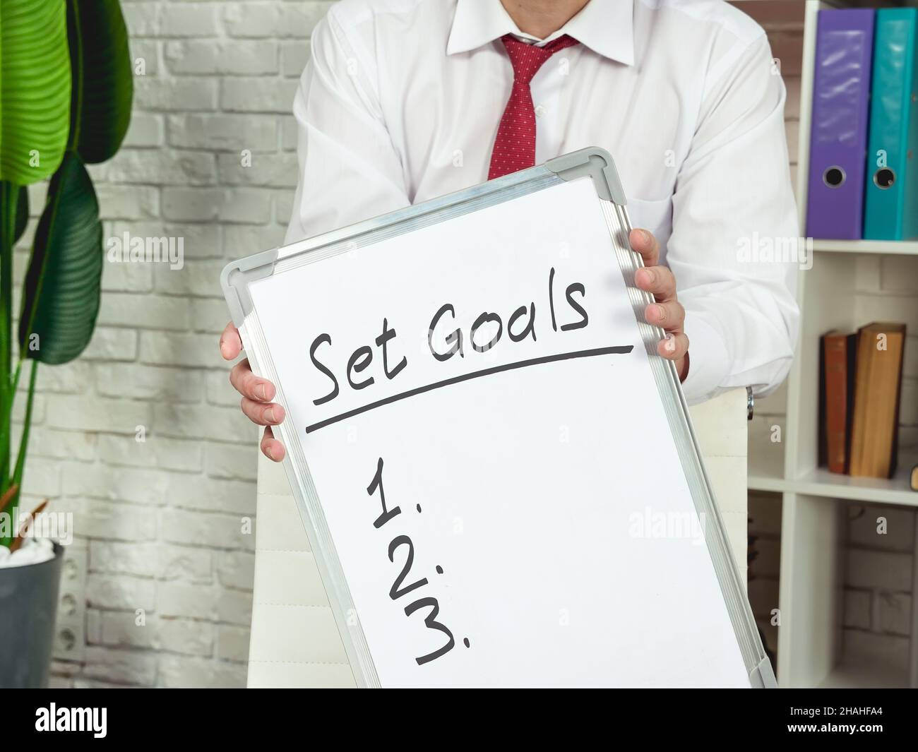 Manager holds board with words Set goals and list Stock Photo - Alamy