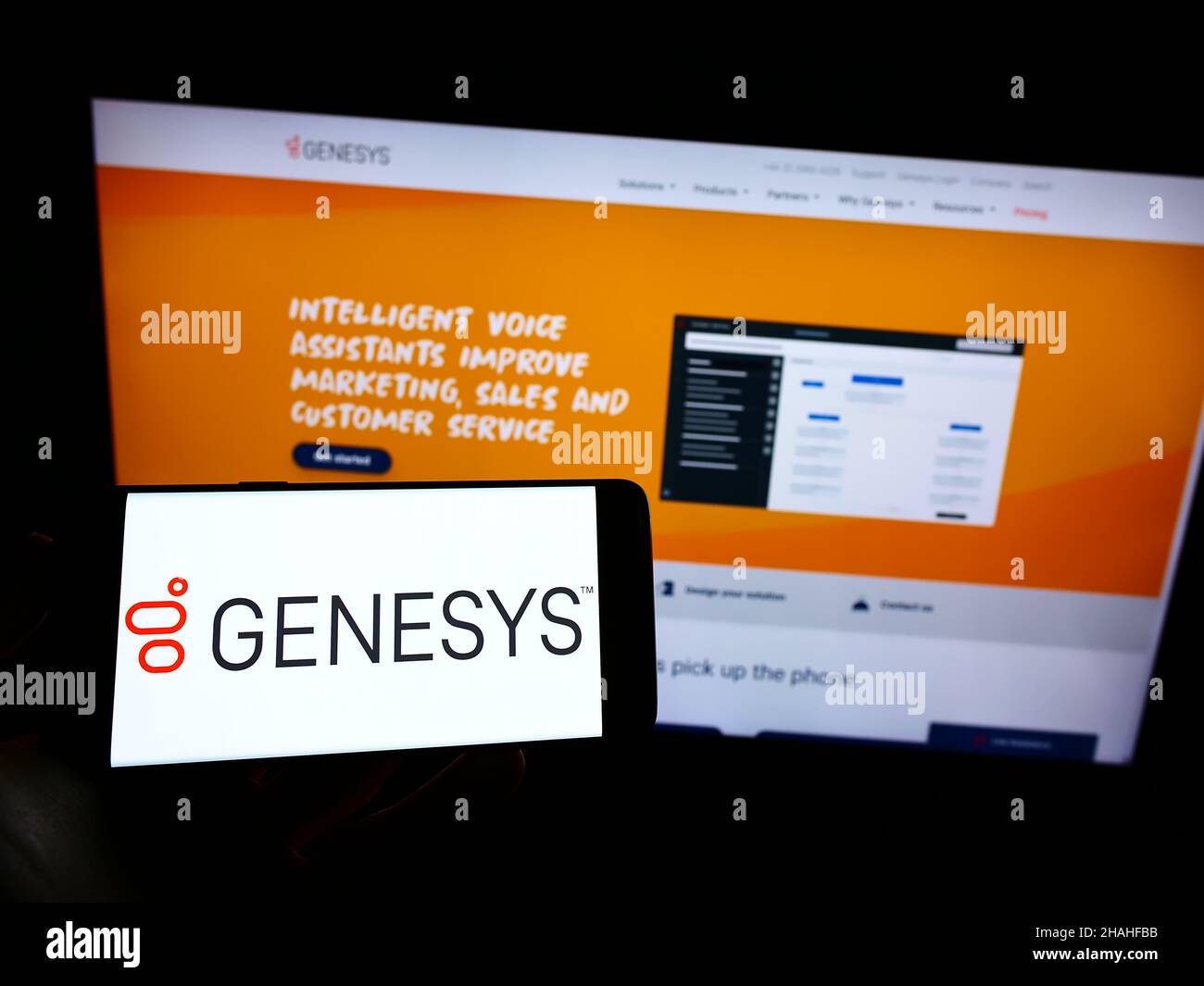 Person holding cellphone with logo of American software company Genesys ...