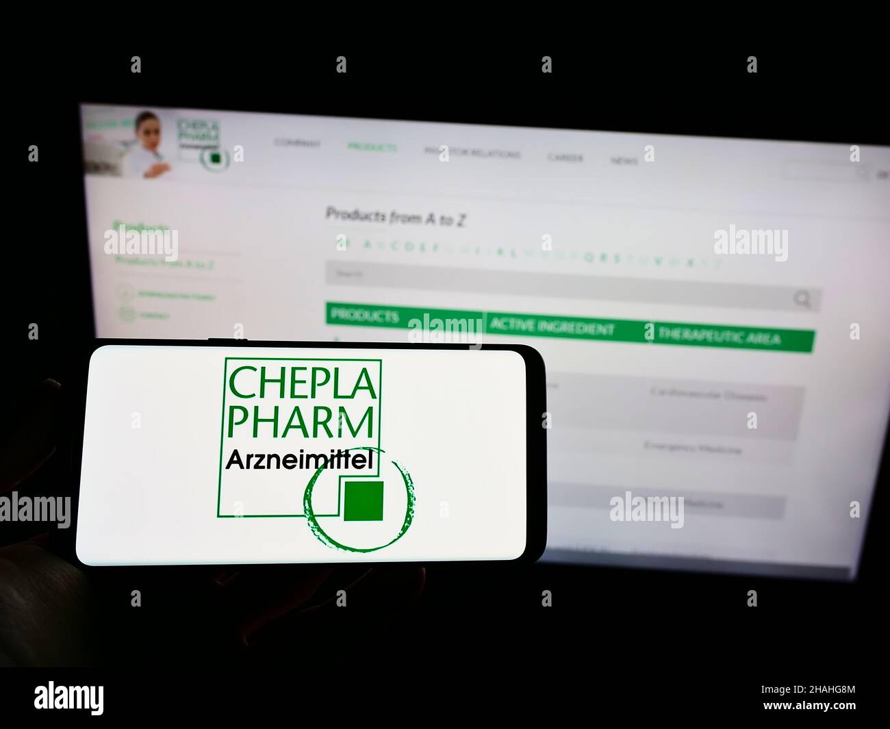 Person holding mobile phone with logo of German pharma company ...