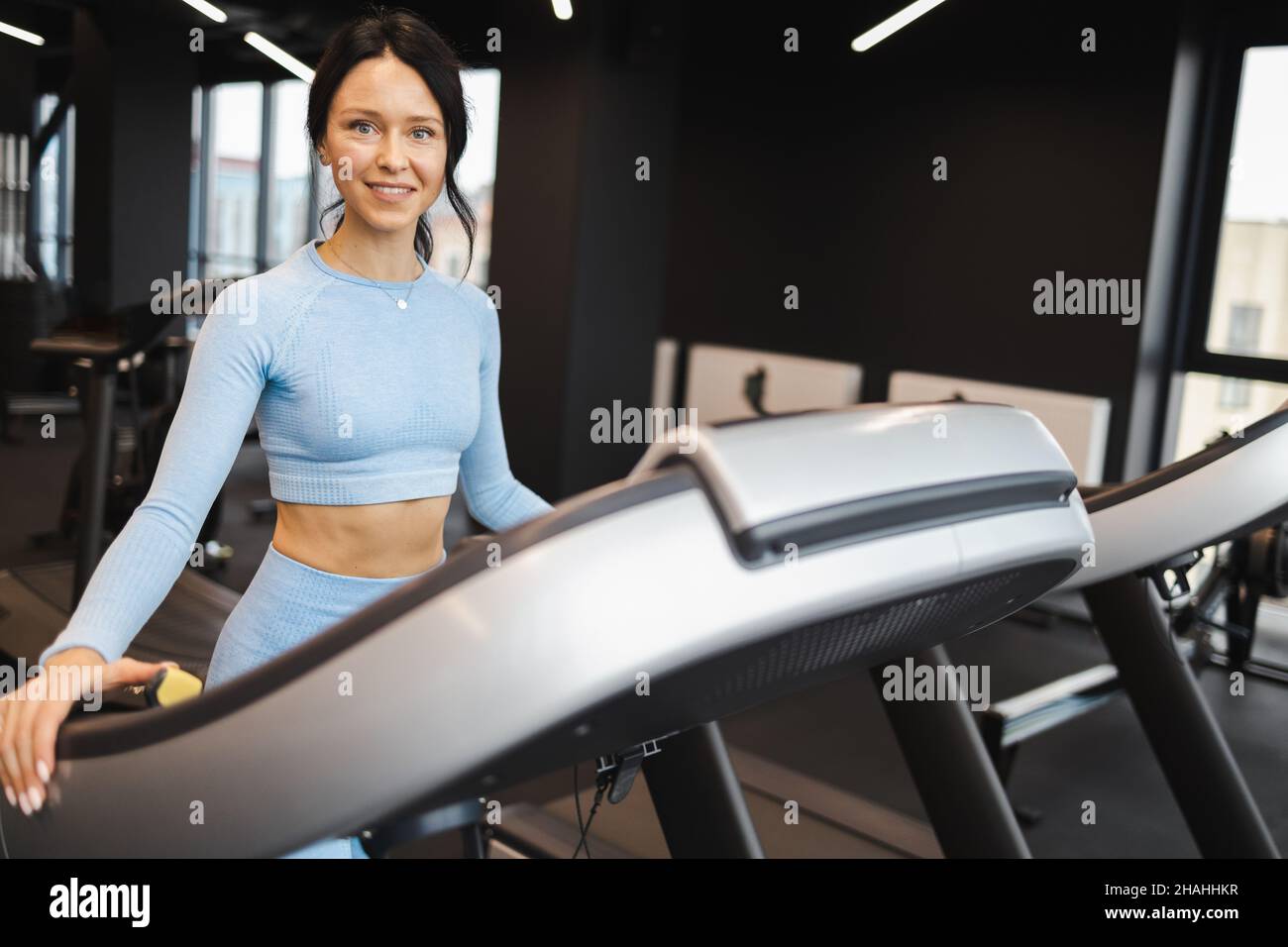 Beautiful woman in a blue sportswear on a treadmill in gym Stock Photo ...