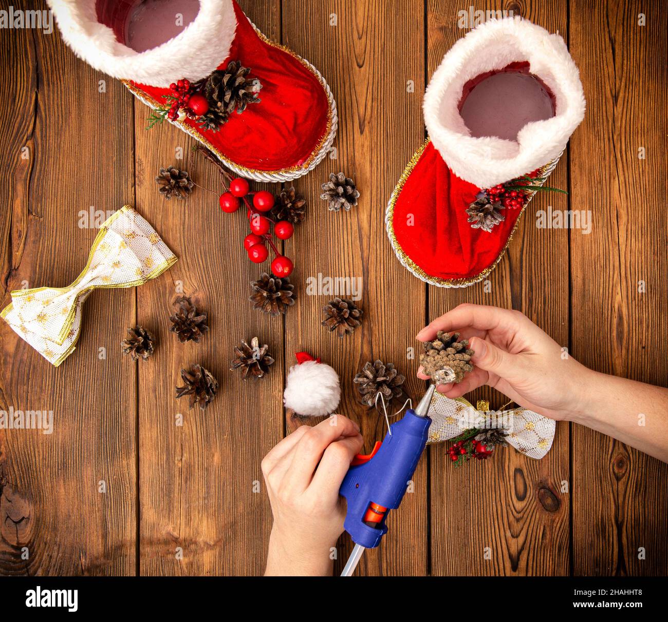 The girl glues a bump on the red boot of santa claus with a glue gun ...