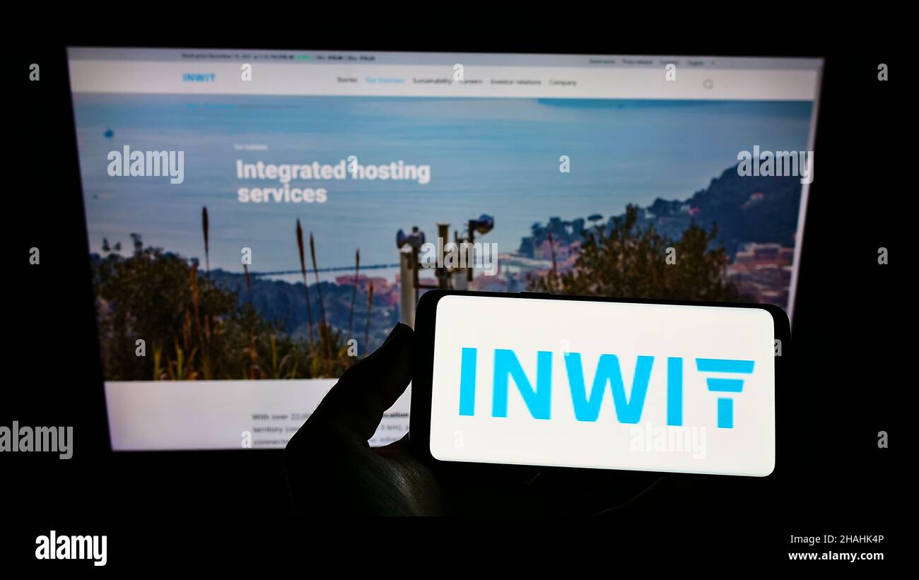 Person holding smartphone with logo of Italian infrastructure company ...