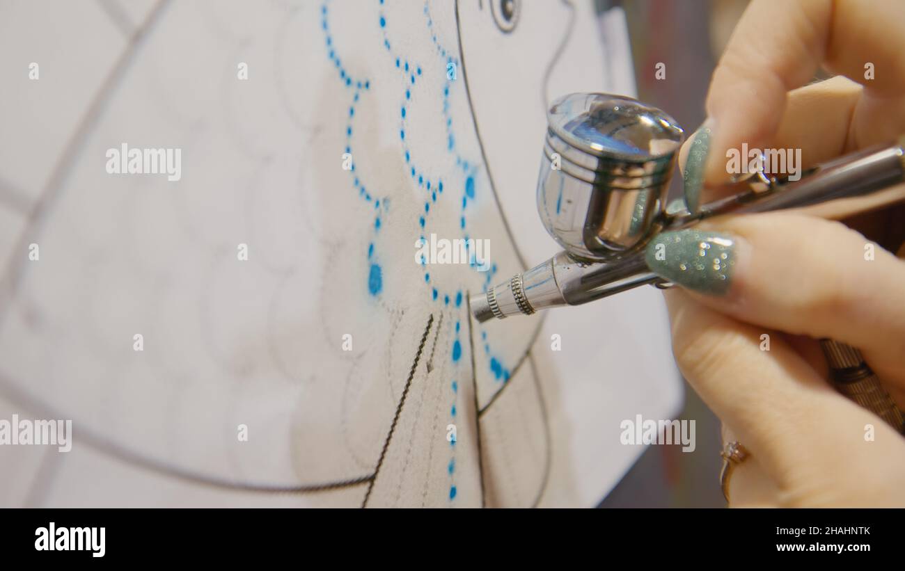 Woman artist learns to paint with airbrush with acrylic dye, paper and ...
