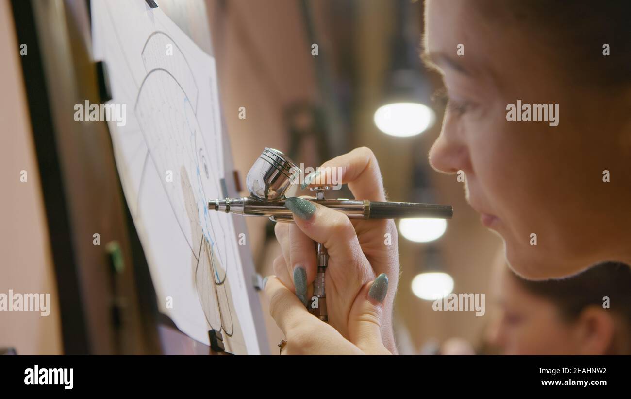 Woman artist learns to paint with airbrush with acrylic dye, paper and ...