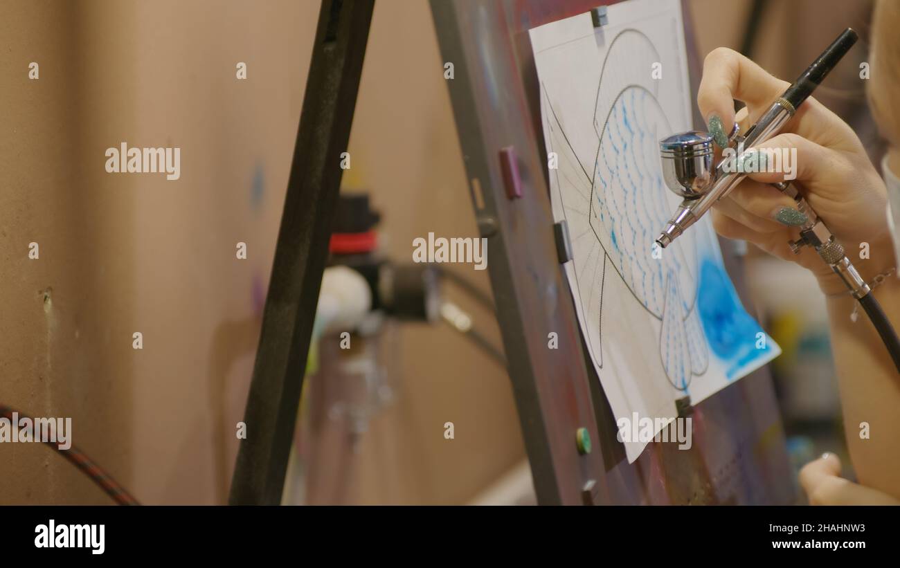 Woman artist learns to paint with airbrush with acrylic dye, paper and ...