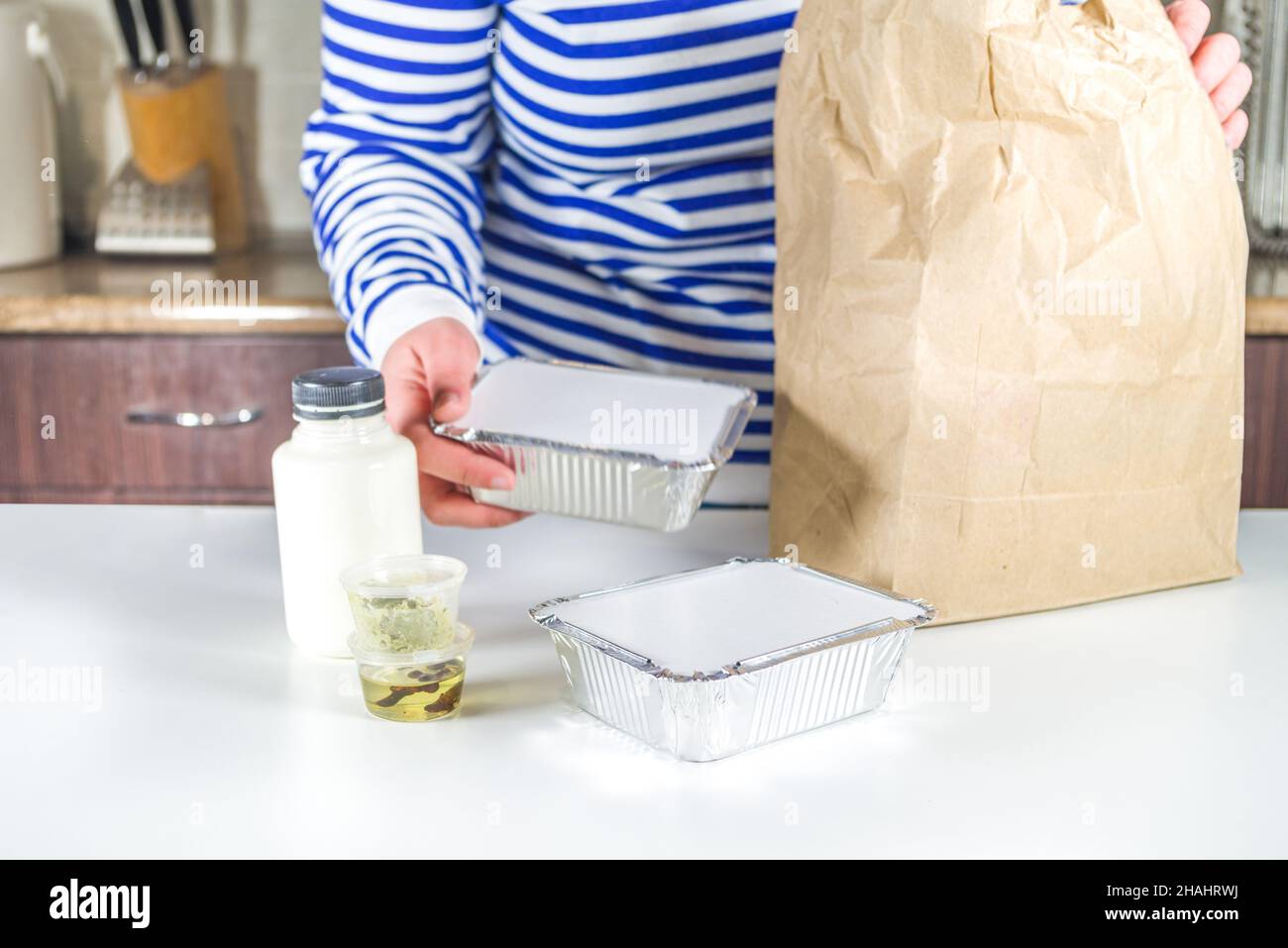 Caucasian woman take apart package with Heat-and-eat meal boxes from ...