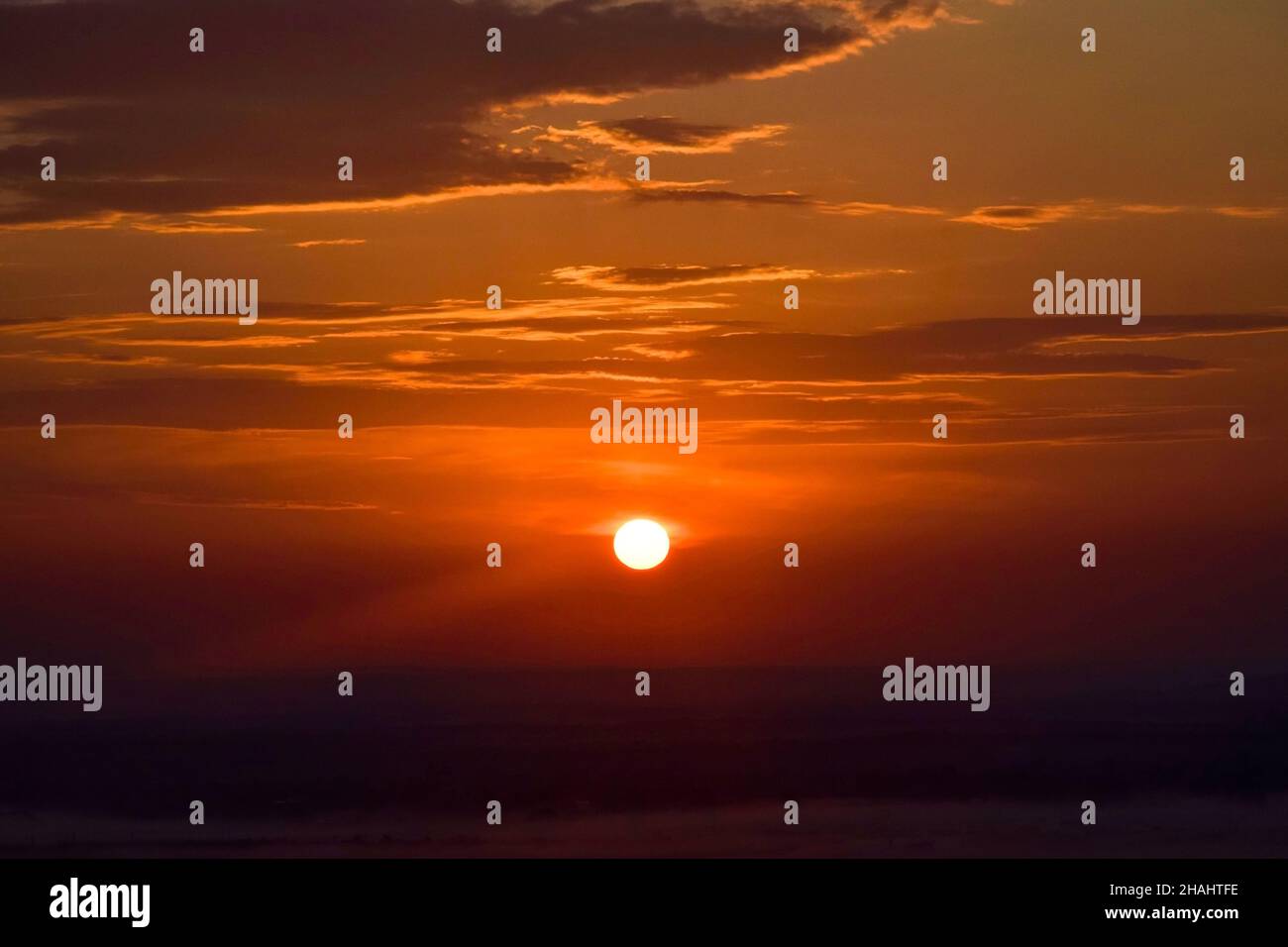 Red sunset sky with clouds over dark foggy landscape. Bright sunny ...