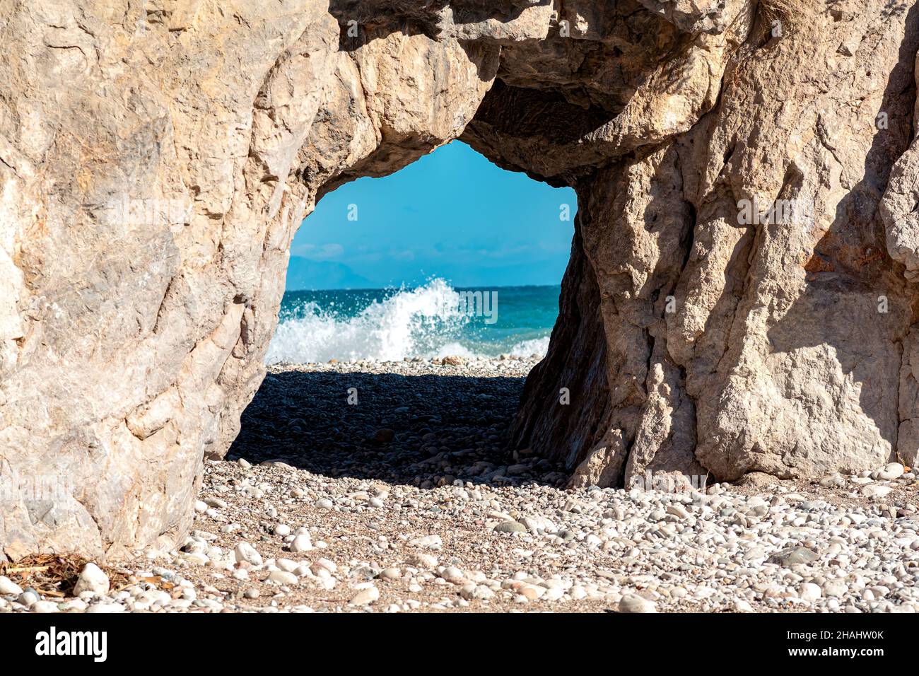 natural stone arch on the seashore, behind which sea surf can be seen ...