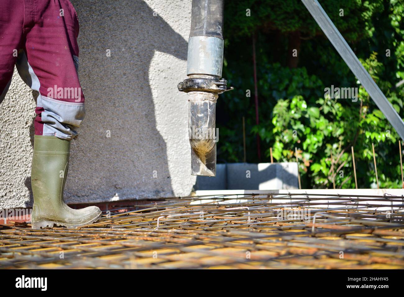 A concrete worker on a construction site concretes walls using a ...