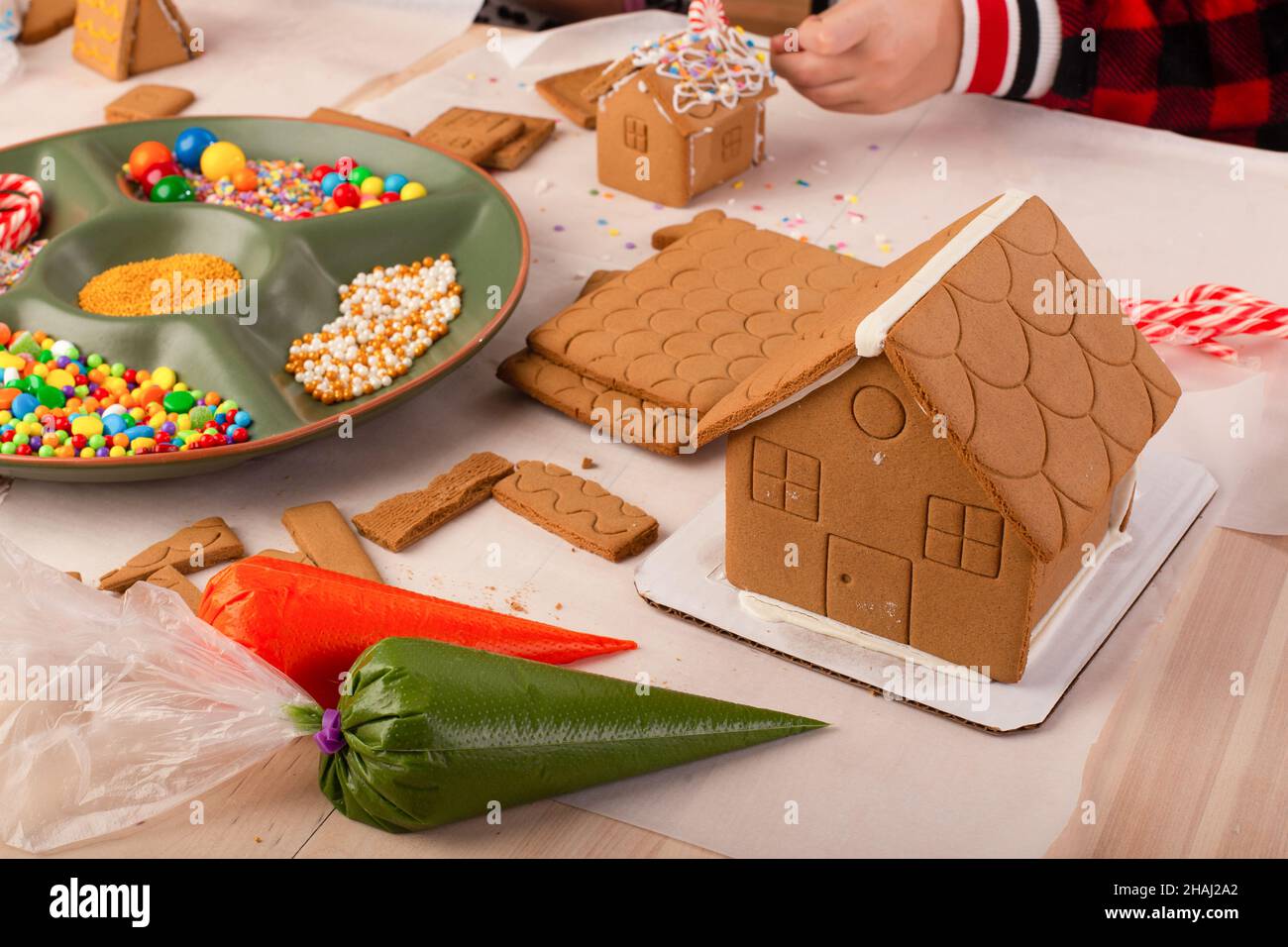 Kids assembling and decorating a gingerbread house at Christmas time ...