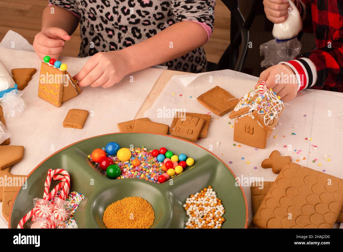 Kids assembling and decorating a gingerbread house at Christmas time ...