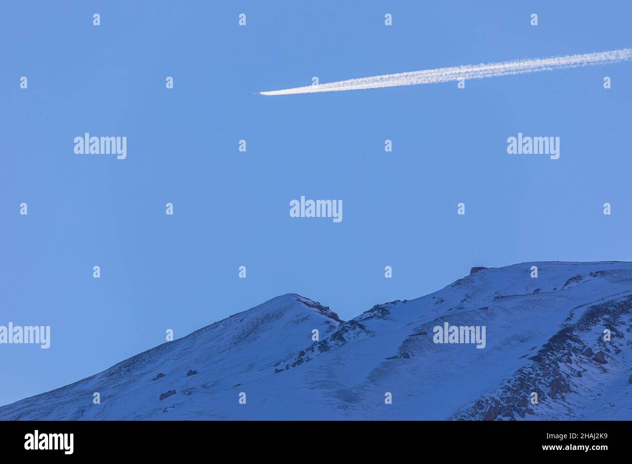 Trail from a flying plane over snow-capped mountains Stock Photo - Alamy