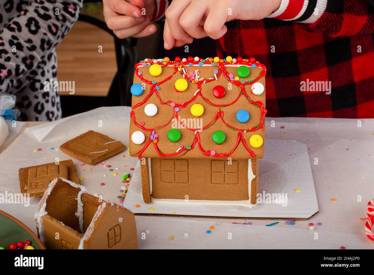 Kids assembling and decorating a gingerbread house at Christmas time ...