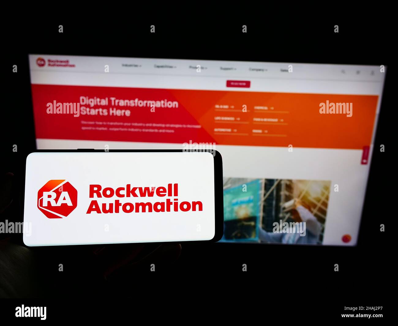 Person holding cellphone with logo of US company Rockwell Automation Inc. on screen in front of ...