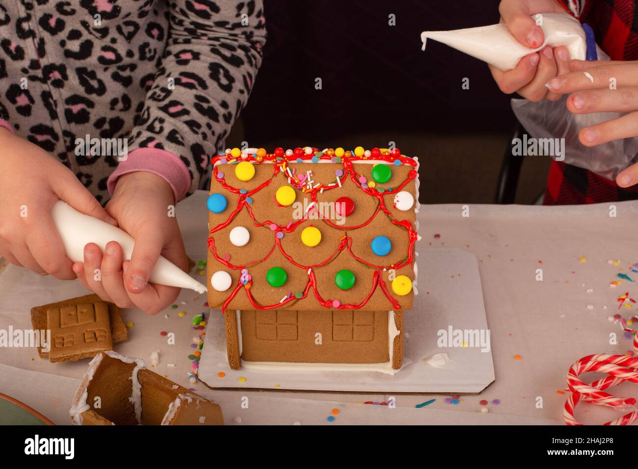Kids assembling and decorating a gingerbread house at Christmas time ...