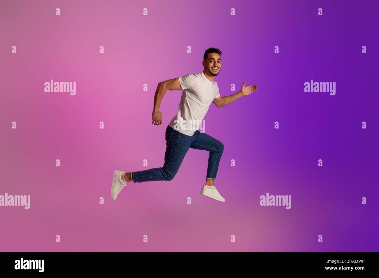 Full length portrait of positive young Arab man in casual wear jumping ...