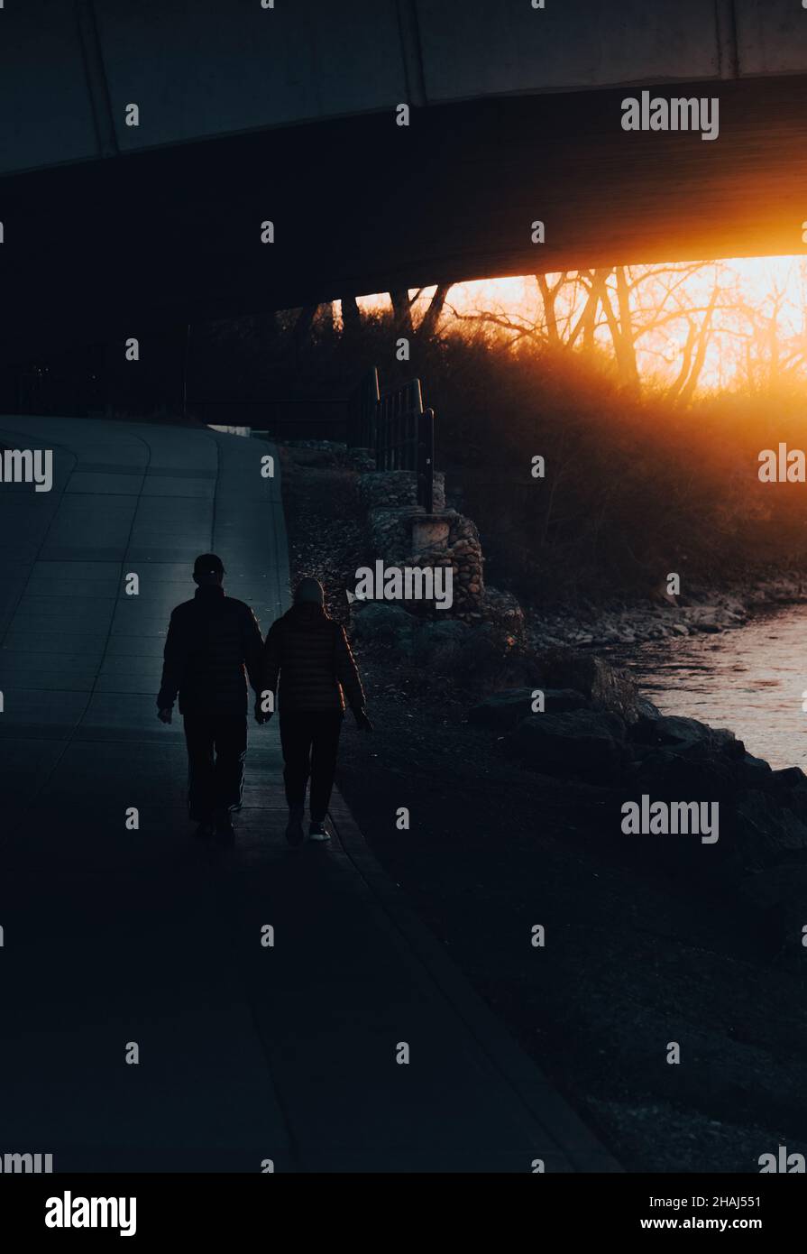 Couple holding hands and walking under a bridge Stock Photo - Alamy