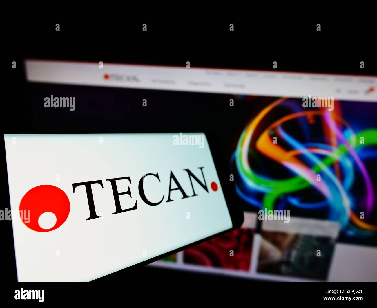 Mobile phone with logo of Swiss laboratory solutions company Tecan Trading AG on screen in front ...