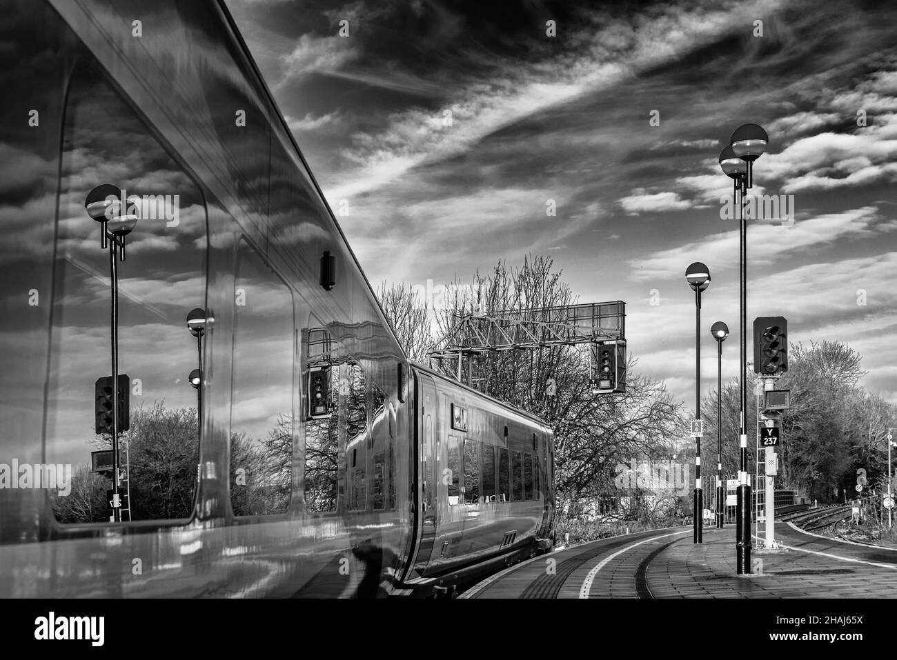 The carriages of a train at a station platform with reflections in its ...