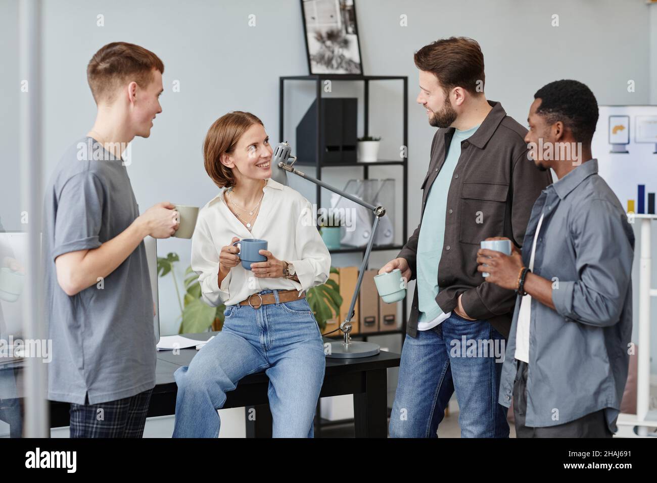 Group of young employees discussing working moments while drinking ...