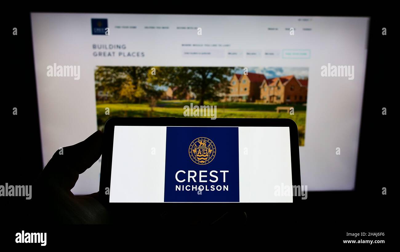 Person holding smartphone with logo of British housebuilding company ...